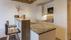 Uma cozinha moderna com teto de madeira, bancada de mármore e dois banquetes.