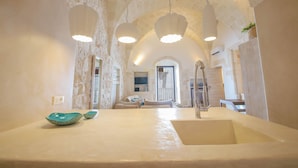 Um banheiro espaçoso com uma banheira grande, pia e duas tigelas decorativas.