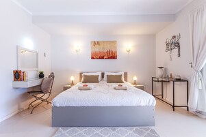 Um quarto moderno com uma cama grande, mesas de cabeceira, uma escrivaninha e uma cadeira.