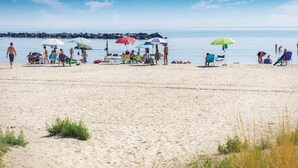 Uma praia com pessoas, guarda-sóis e cadeiras.