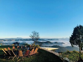 Terraço com cadeiras e área de churrasco com vista para uma paisagem montanhosa e nevoenta.