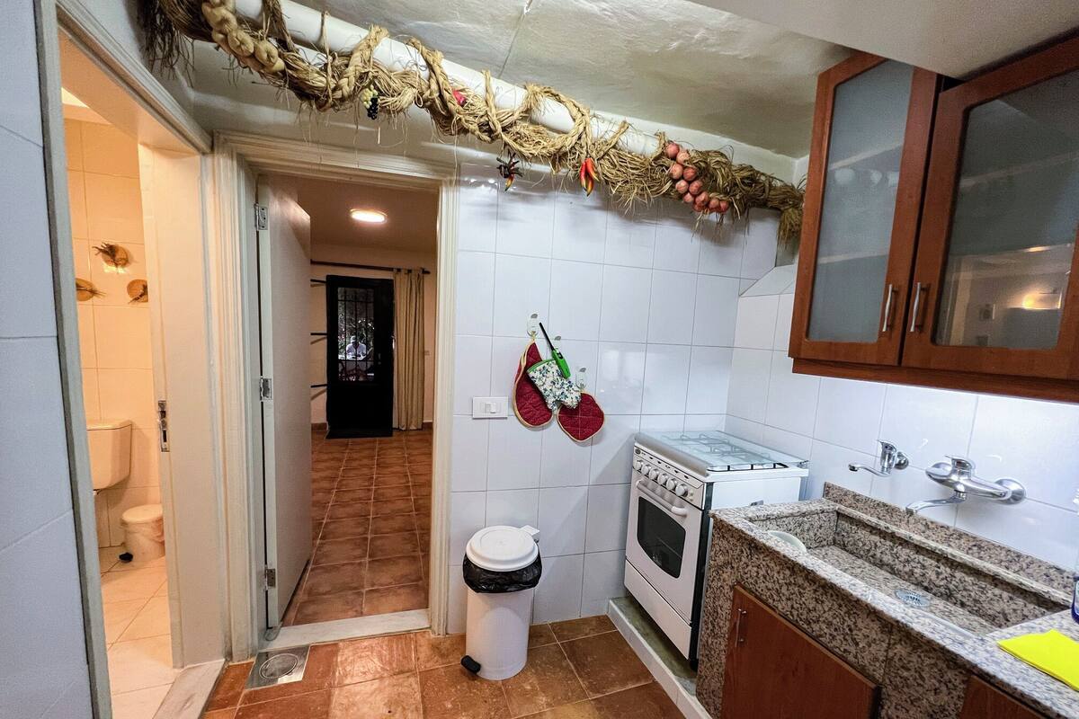 Uma cozinha compacta com fogão a gás, lixeira e pia.