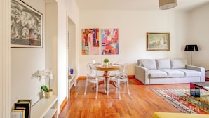 Uma sala de estar moderna com uma mesa de jantar, cadeiras transparentes, um sofá e obras de arte nas paredes.