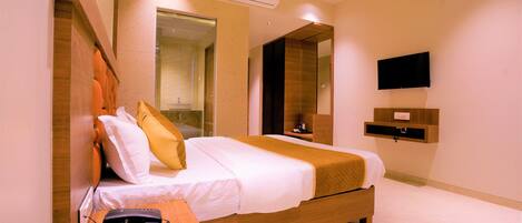 Quarto de hotel moderno com uma cama grande, mesa de cabeceira com telefone, espelho e televisão na parede.