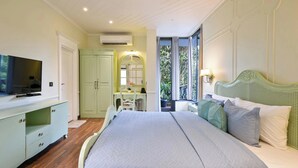 Quarto com cama, televisão, guarda-roupa e janela com vista para o verde.