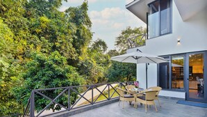 Uma casa moderna com varanda, mobiliário de exterior e vegetação exuberante.
