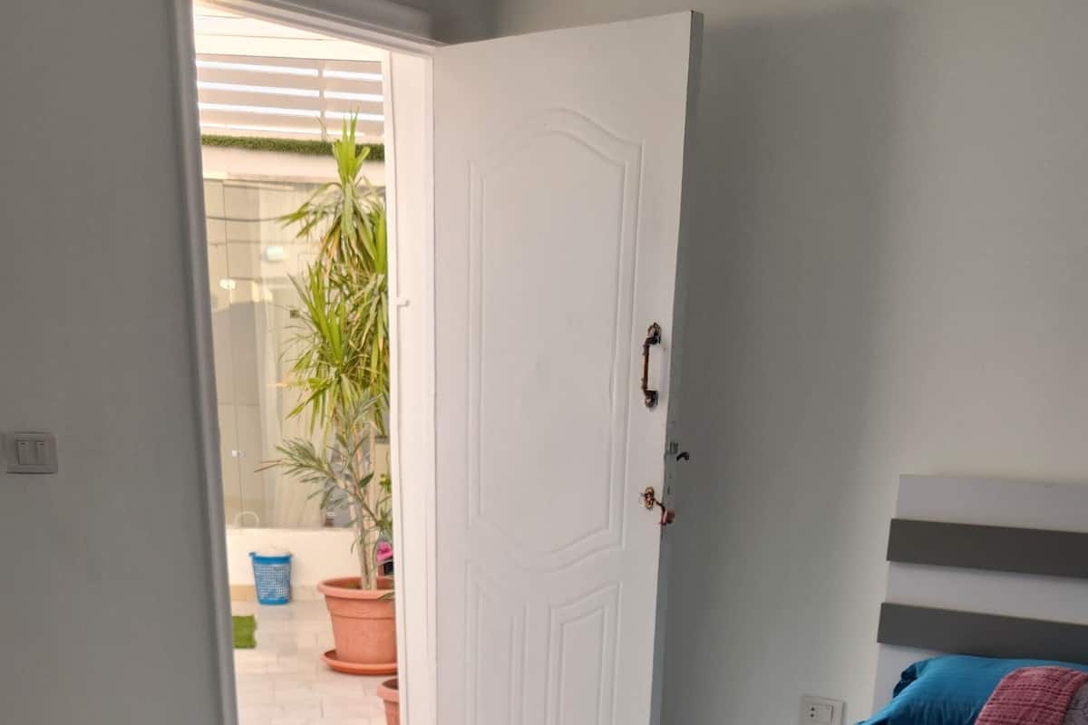 Quarto com cama, porta e vista para o exterior.