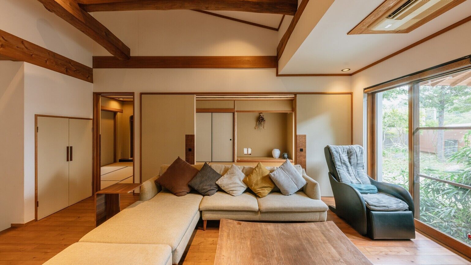 Uma sala de estar moderna com um sofá, uma poltrona e uma mesa de centro de madeira.