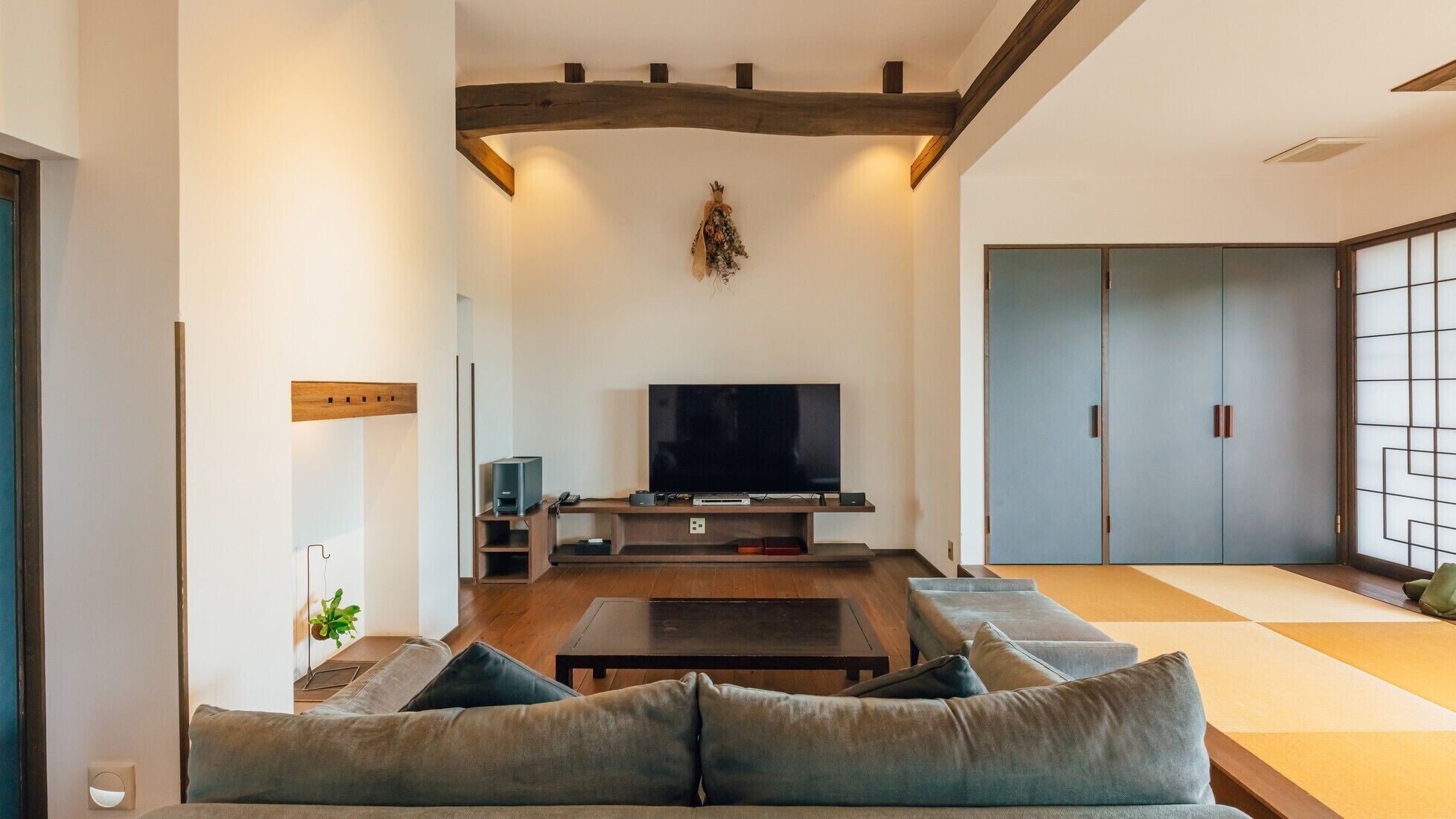 Uma sala de estar moderna com televisão, sofá e vigas de madeira no teto.