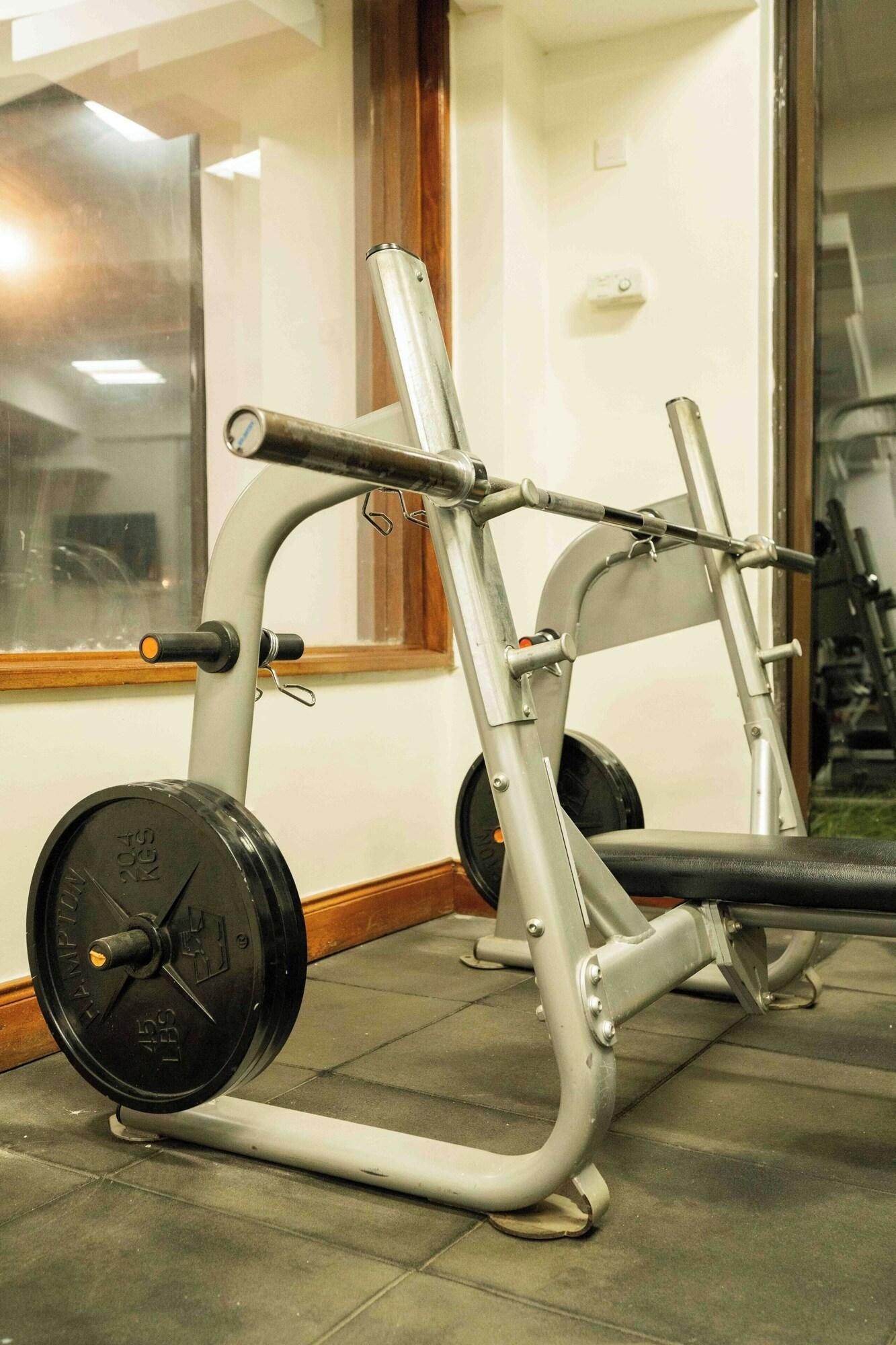 Uma academia com equipamentos de musculação, incluindo um banco e um suporte para agachamento.