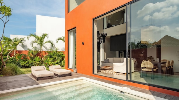 Uma casa moderna com piscina, móveis de jardim e vegetação exuberante.