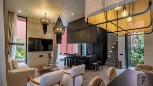 Uma sala de estar moderna com sofá, cadeiras, mesa de centro, mesa de jantar e área de cozinha com banquetas.
