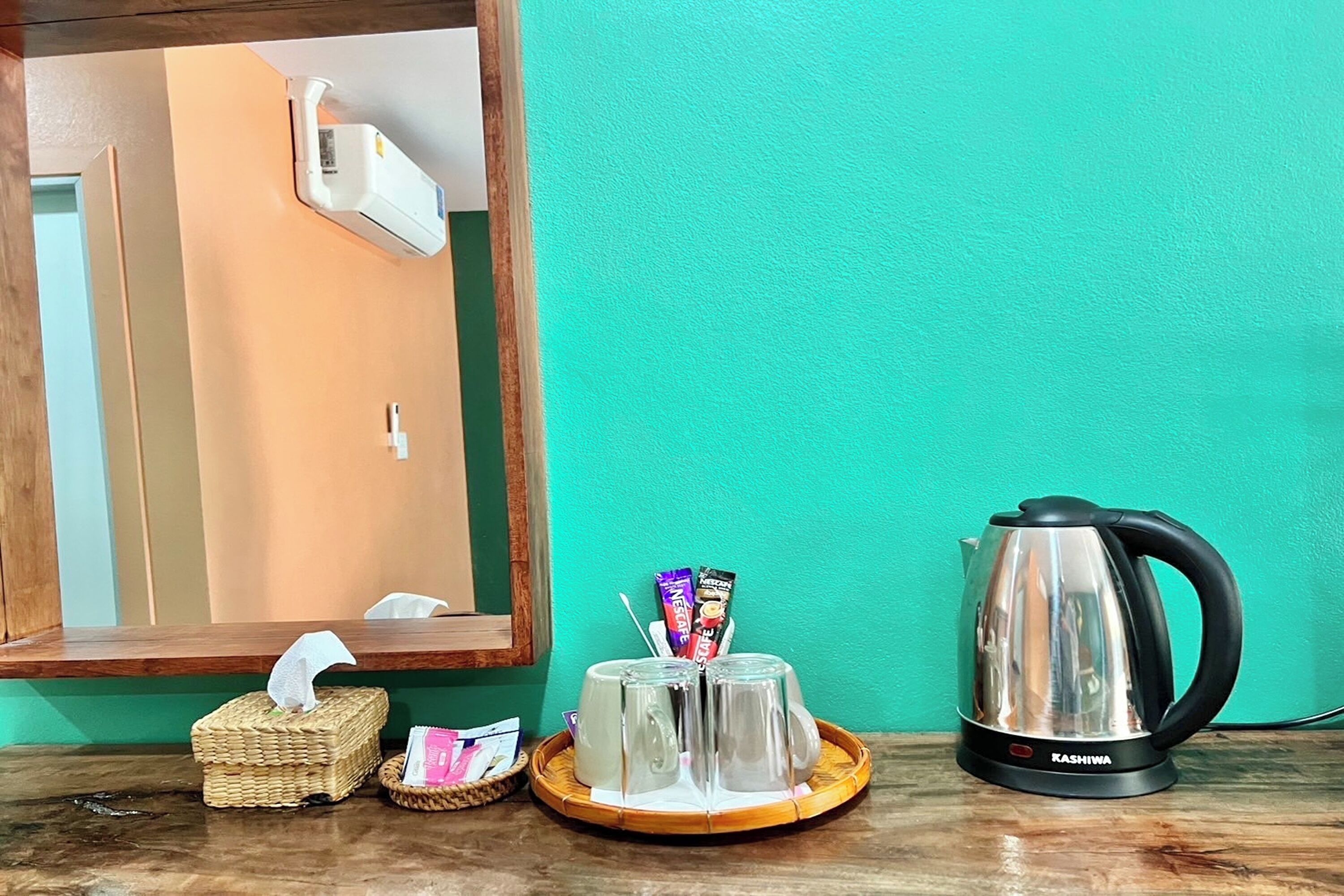 Uma bancada de cozinha com uma chaleira, uma caixa de lenços e uma bandeja com chá e petiscos.