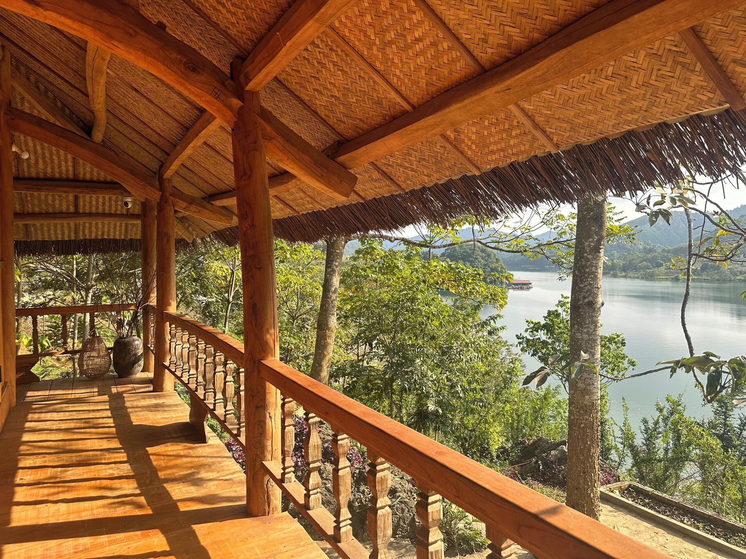 Um deck de madeira com telhado de palha com vista para um lago.