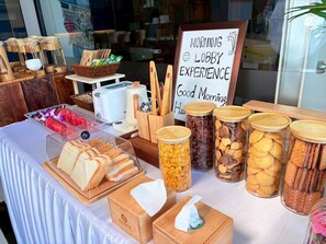 Uma mesa de café da manhã com pães, biscoitos e uma placa que diz 'MORNING LOBBY EXPERIENCE'.
