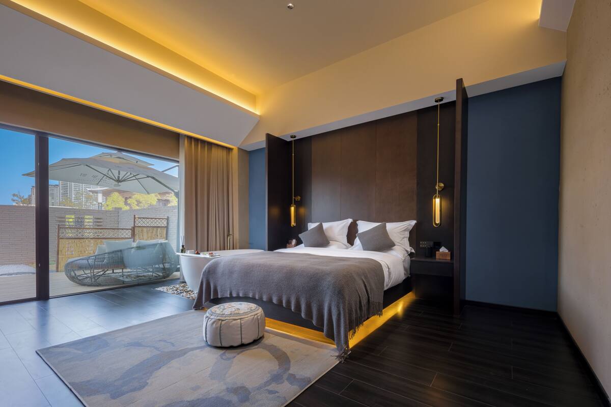 Quarto moderno com uma cama grande, divisória de vidro e vista para o exterior.
