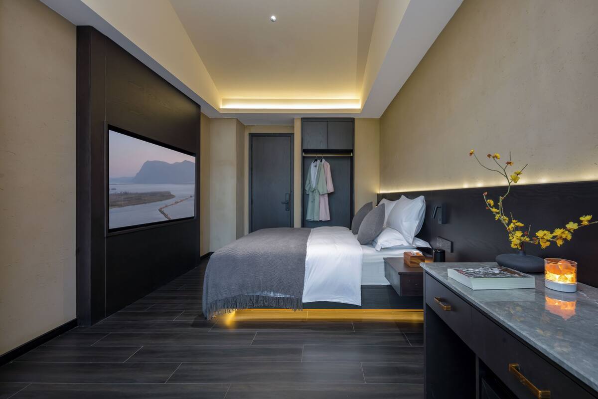 Quarto de hotel moderno com cama, mesa de cabeceira e vista para a praia.