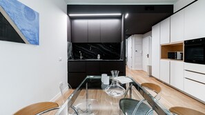 Uma cozinha moderna com mesa de jantar de vidro, armários pretos e painel de backsplash de mármore.