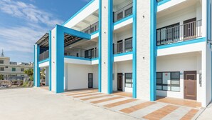 Um edifício com vários andares e design moderno, com varandas, galeria coberta e céu claro.