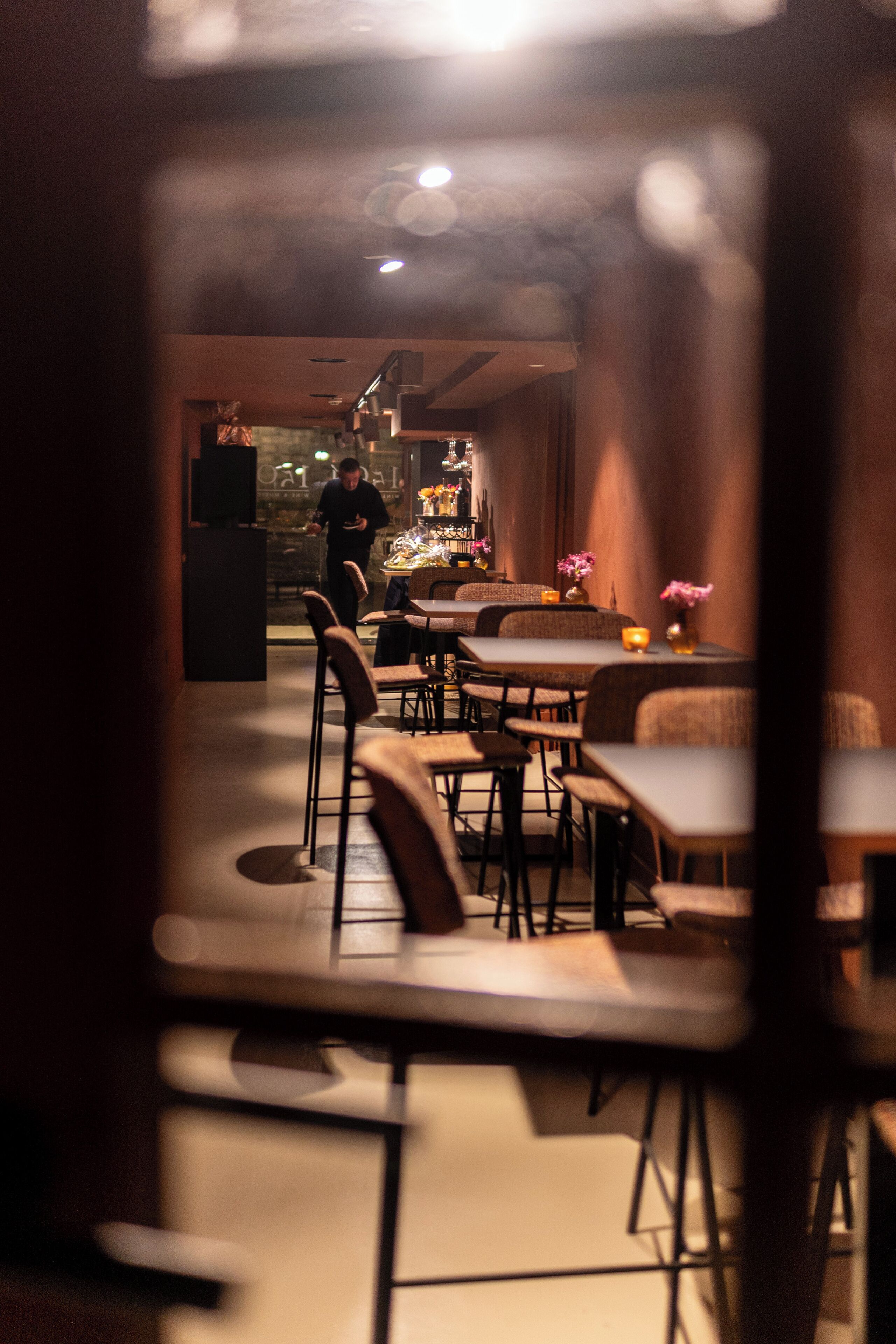 Interior de restaurante com iluminação suave, mesas e cadeiras dispostas para refeições.