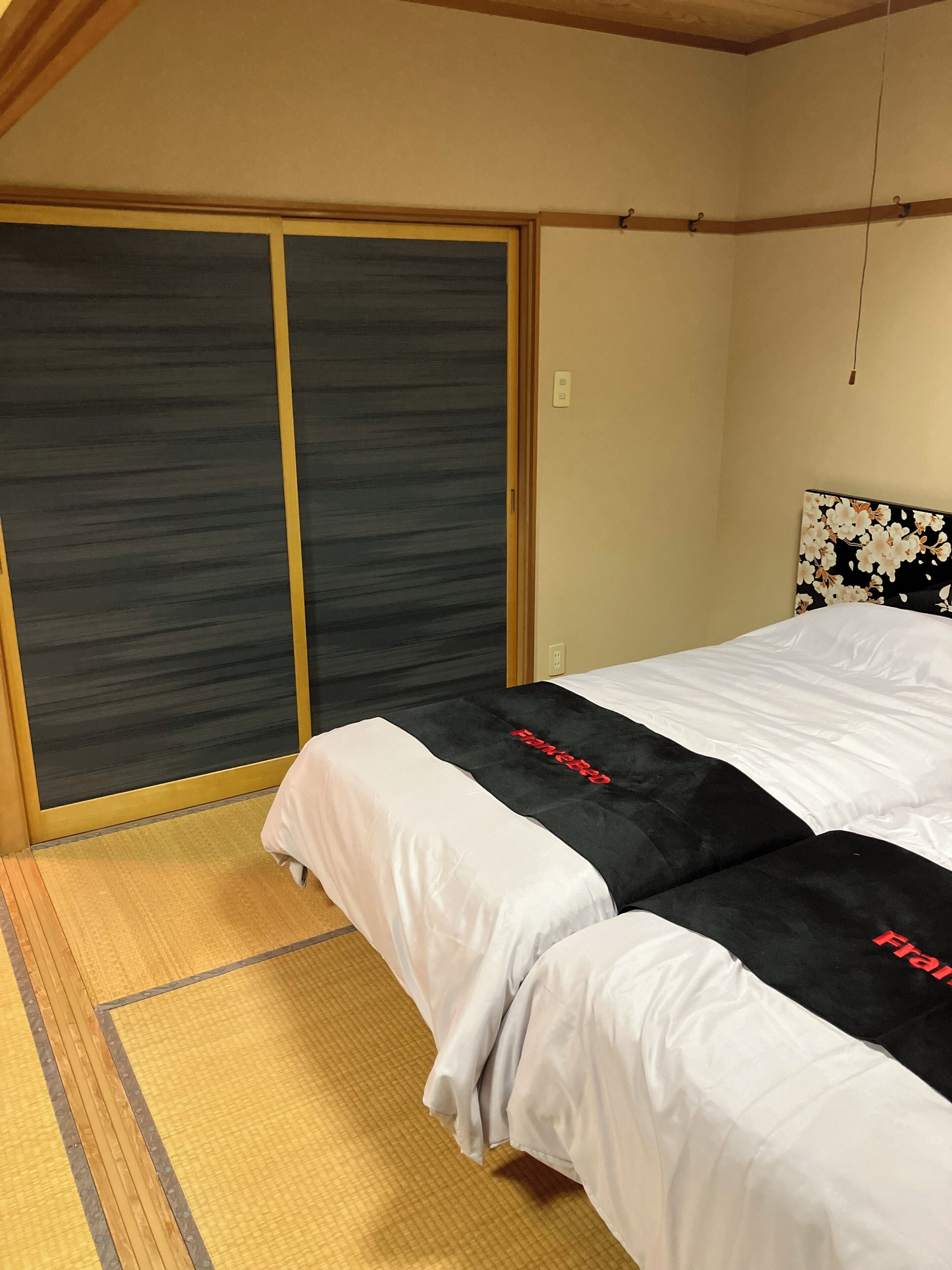 Quarto de hotel com cama, uma grande porta deslizante e piso de esteira de tatame.