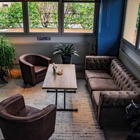 Um espaço de estar aconchegante com sofá de couro, poltrona estofada e uma pequena mesa.