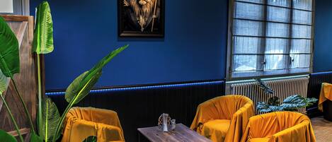 Um quarto com parede azul escura, um quadro com a imagem de um leão e móveis com revestimento amarelo.