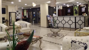 Um hall de hotel com assentos confortáveis, balcão de recepção e um vaso decorativo.