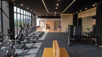 Uma academia com equipamentos de ginástica, um banco e halteres.