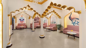 Um hall de entrada luxuoso com arcos elaborados, assentos confortáveis e um candelabro.
