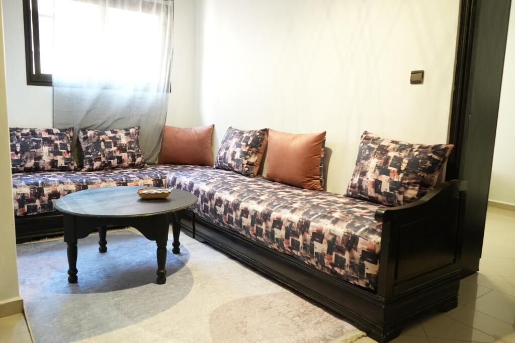 Uma sala de estar moderna com um sofá de canto, uma mesa de centro redonda e almofadas estampadas.
