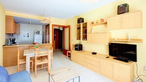 Espaço compacto com cozinha compacta, área de refeições, TV e um pequeno espaço para sentar.