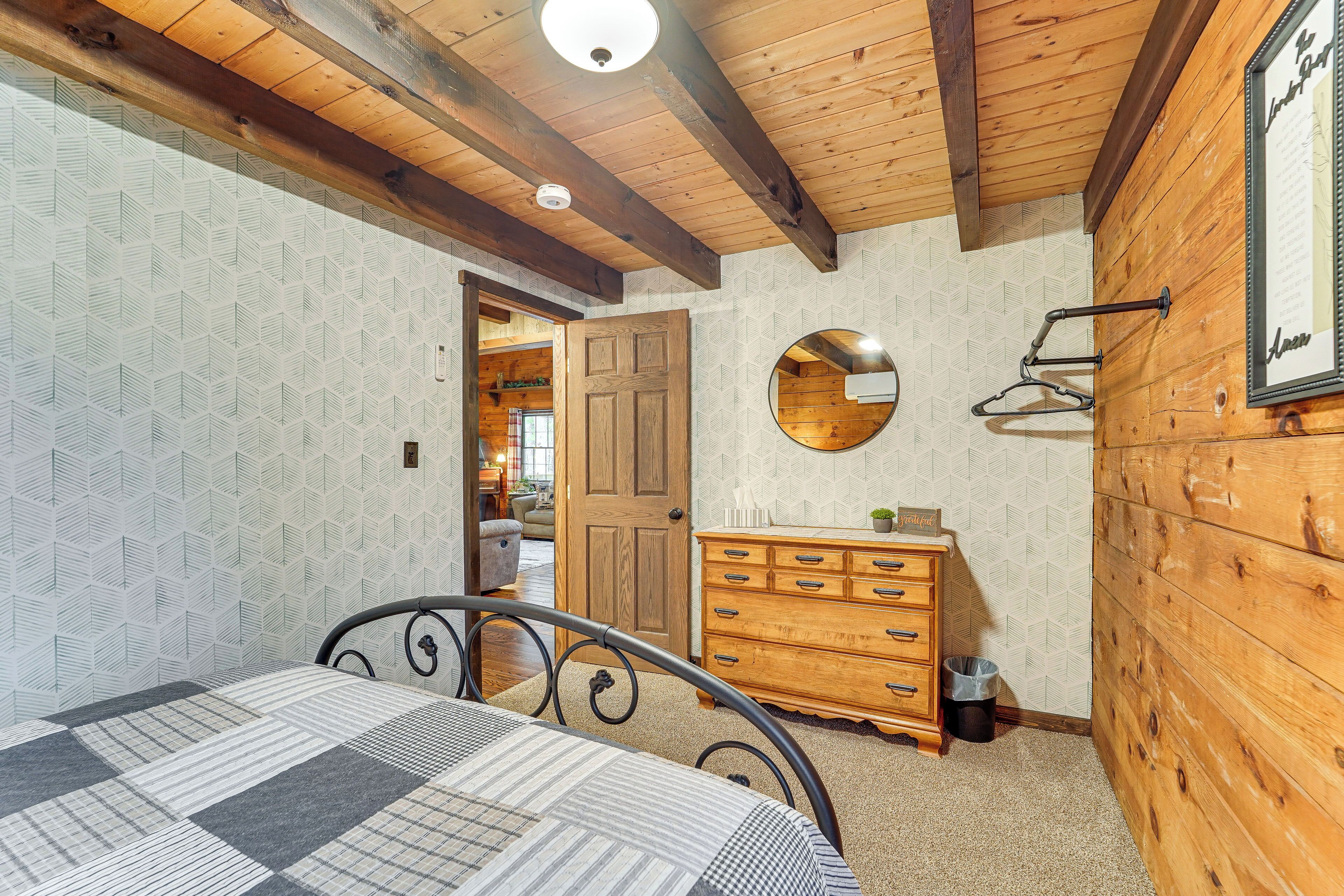 Quarto com cama, penteadeira de madeira e espelho na parede.