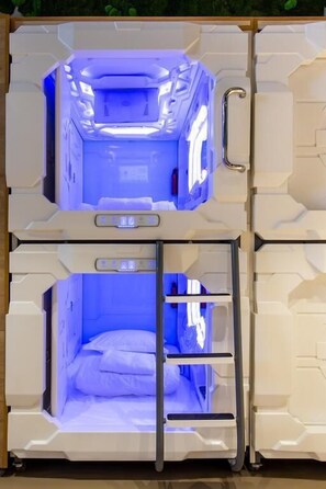 Um hotel cápsula com dois quartos, cada um com uma cama e um painel de controle.