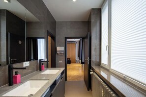 Uma casa de banho moderna com duas pias, um espelho grande e uma cabine de duche.
