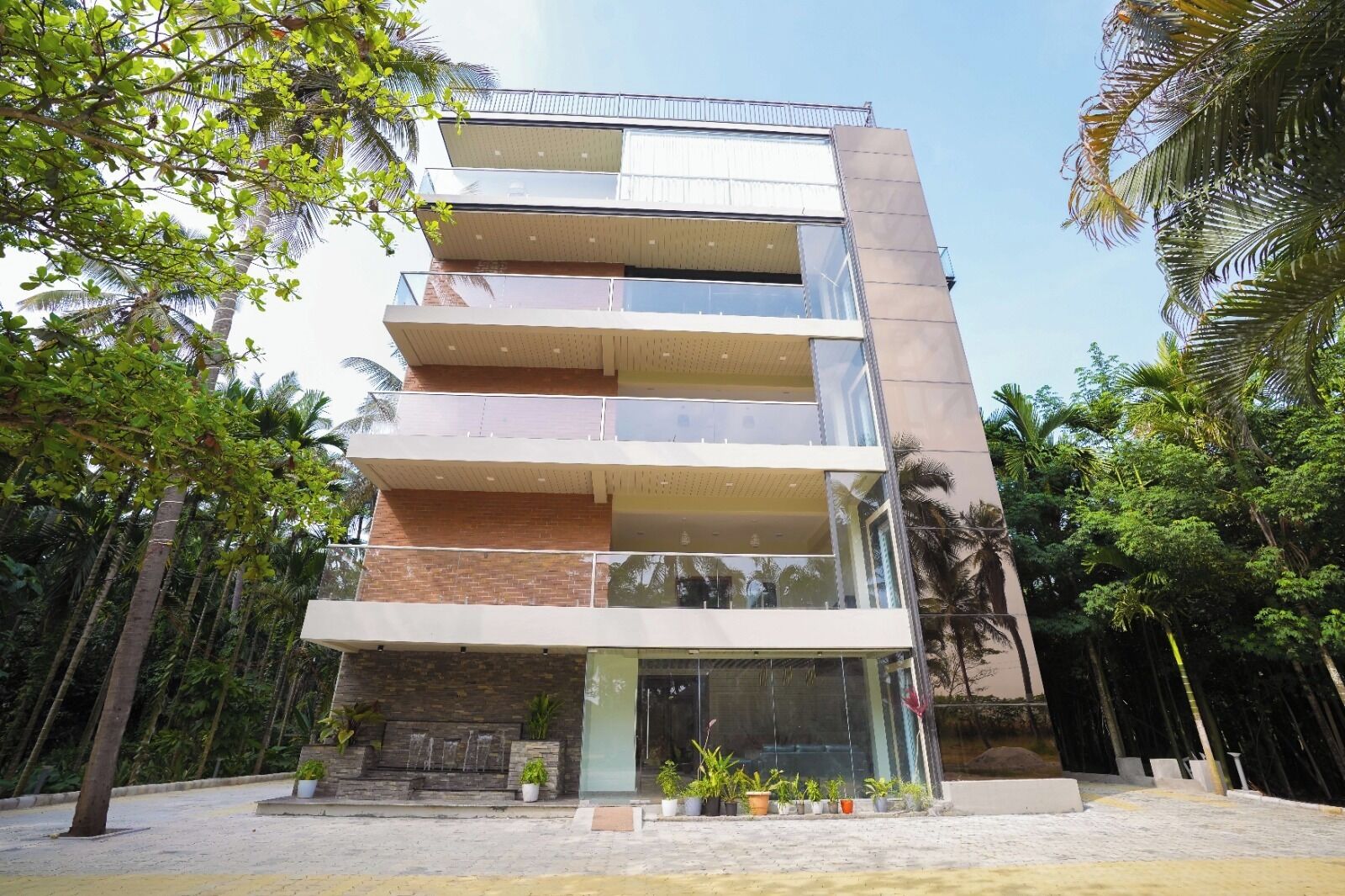 Um edifício com várias andares e varandas, rodeado por vegetação exuberante.