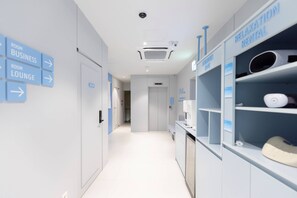 Corredor de hotel com placas de sinalização para salas de negócios e um lounge, uma kitchenette e uma área de aluguel para relaxamento.