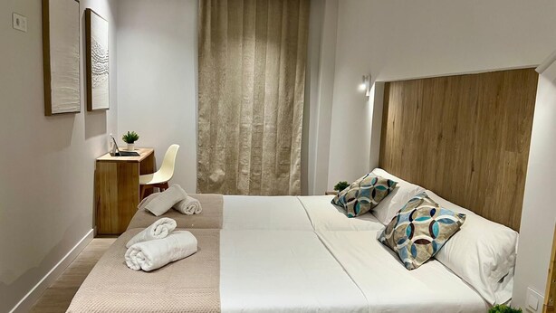 Quarto de hotel moderno com uma cama grande, uma escrivaninha e uma cadeira.
