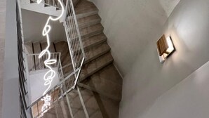 Uma escadaria em espiral com design moderno, com um lustre apresentando um padrão semelhante a caligrafia.