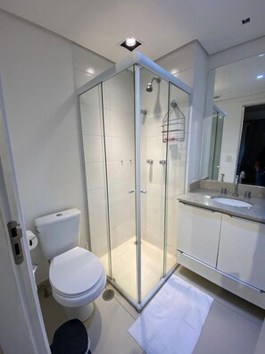 Uma casa de banho moderna com cabine de duche em vidro, sanita e lavatório com bancada.