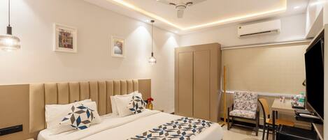 Quarto de hotel moderno com uma cama grande, uma mesa com cadeira, ventoinha no teto e ar condicionado.