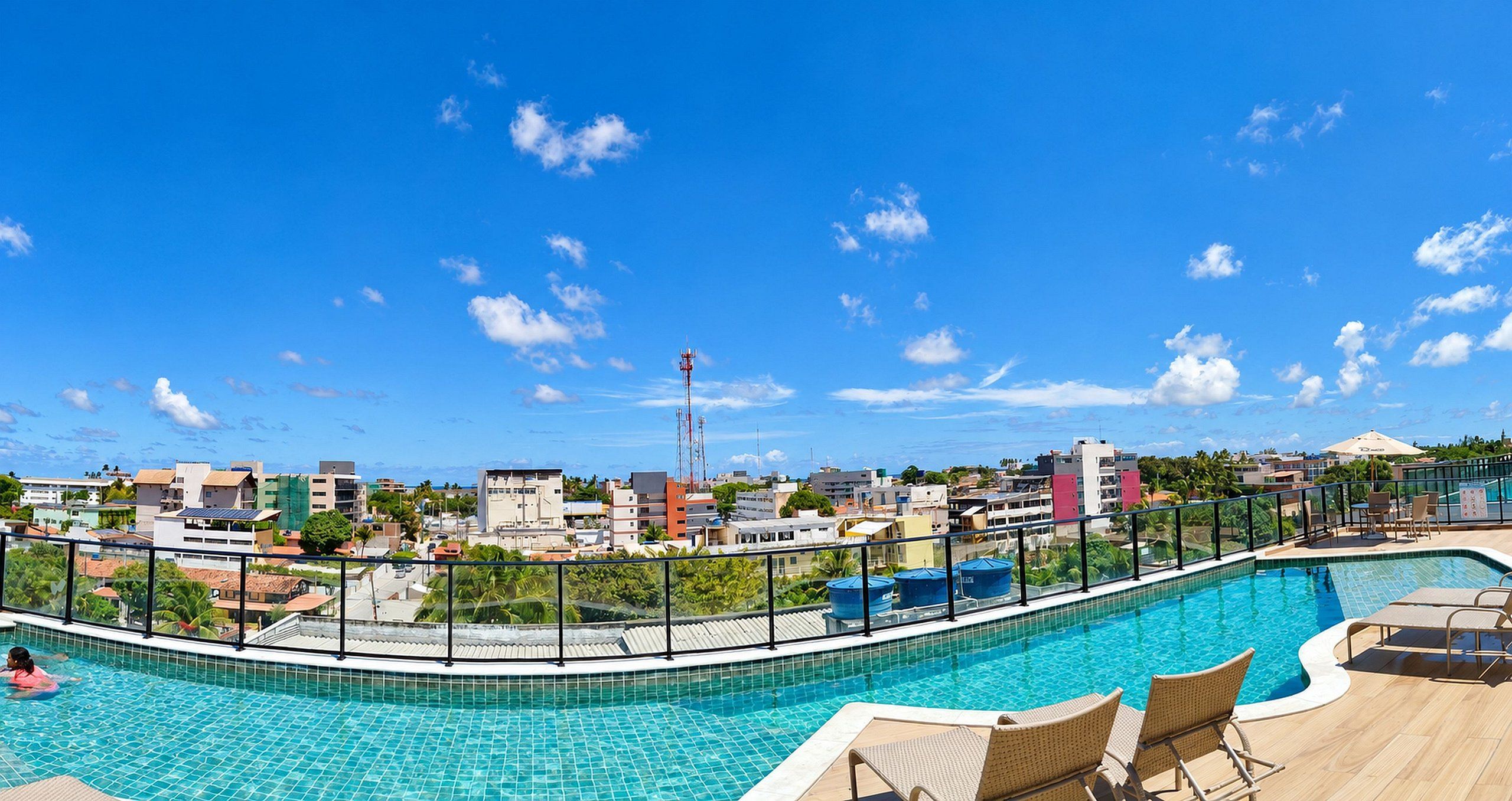 Piscina com vista para um horizonte urbano, incluindo edifícios e céu claro.