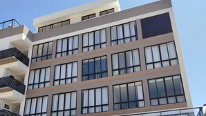 Um edifício de vários andares com design arquitetônico moderno, com grandes janelas e varandas.