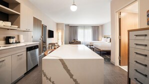Quarto de hotel moderno com cozinha, uma ilha central grande, cama e guarda-roupa.