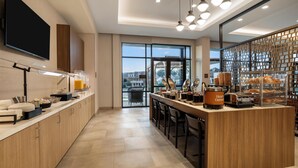 Cozinha moderna com balcão de refeições, TV de tela plana e vista da cidade.