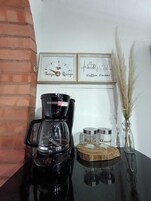 Máquina de café sobre uma mesa com dois recipientes para café e um objeto decorativo.