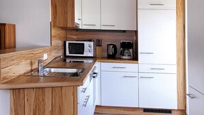Uma cafeteira/bule, um frigorífico, um micro-ondas, um forno 