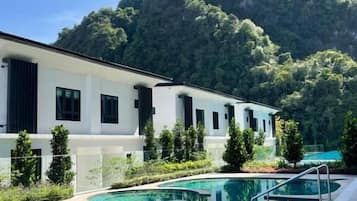 Um hotel moderno com piscina e montanhas ao fundo.