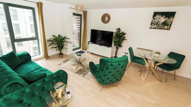Uma sala de estar moderna com um sofá verde, uma mesa de centro de vidro e uma televisão de tela plana.