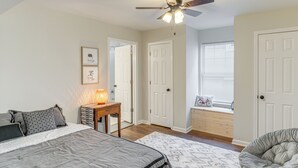 Quarto com cama, escrivaninha, cadeira e ventoinha no teto.